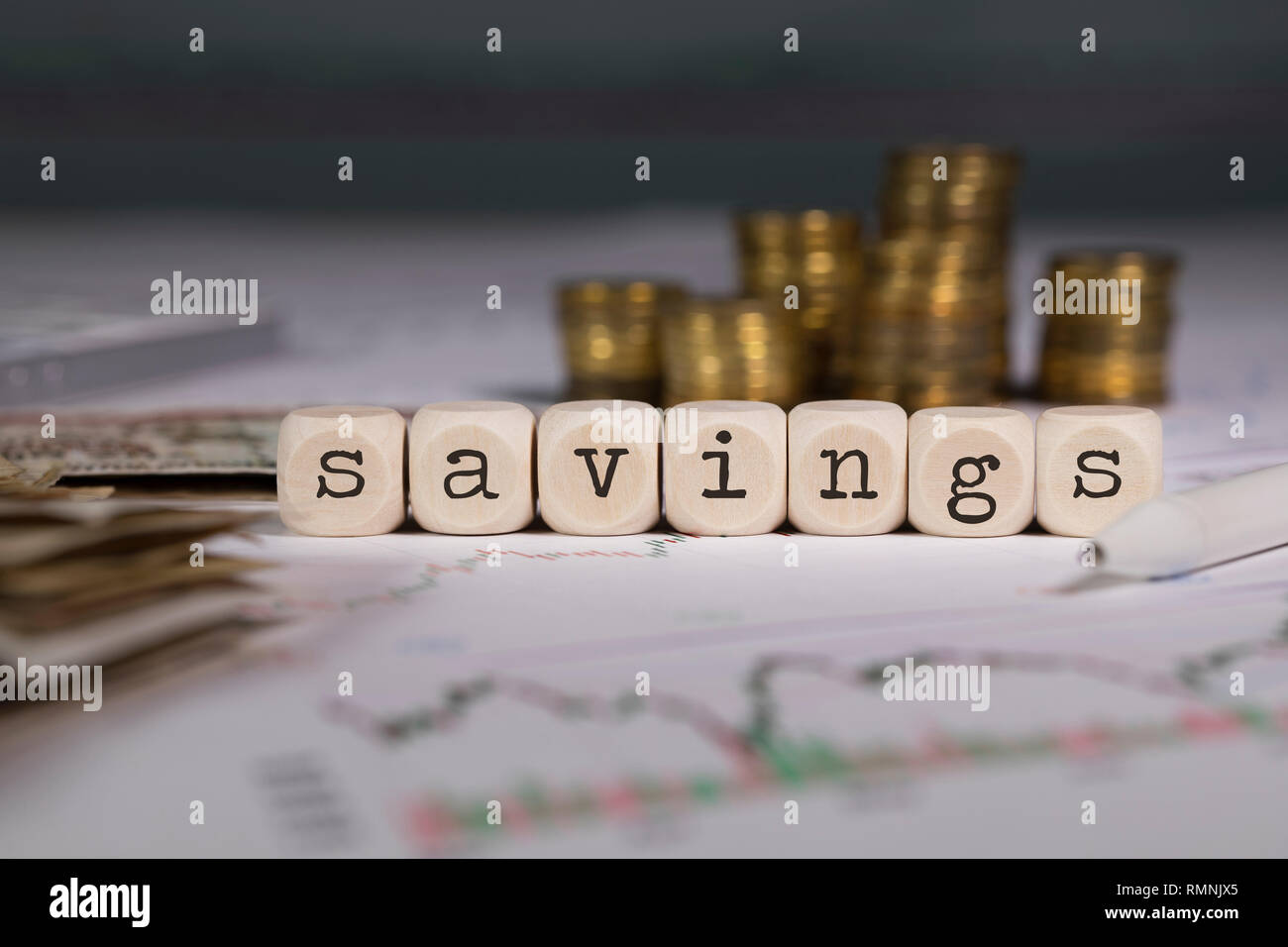 Word SAVINGS composed of wooden letter. Stacks of coins in the ...