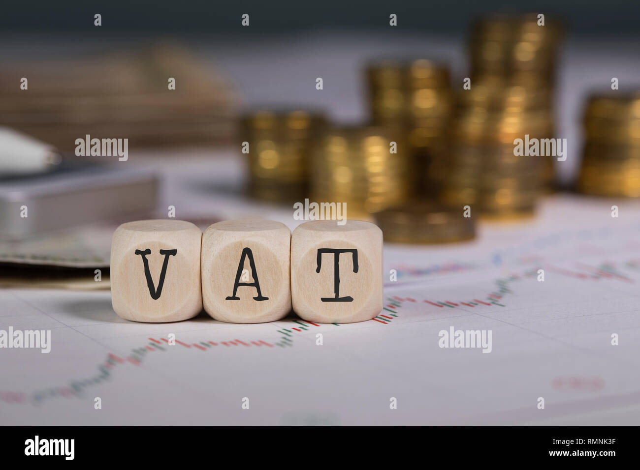 Abbreviation VAT composed of wooden letter. Stacks of coins in the ...