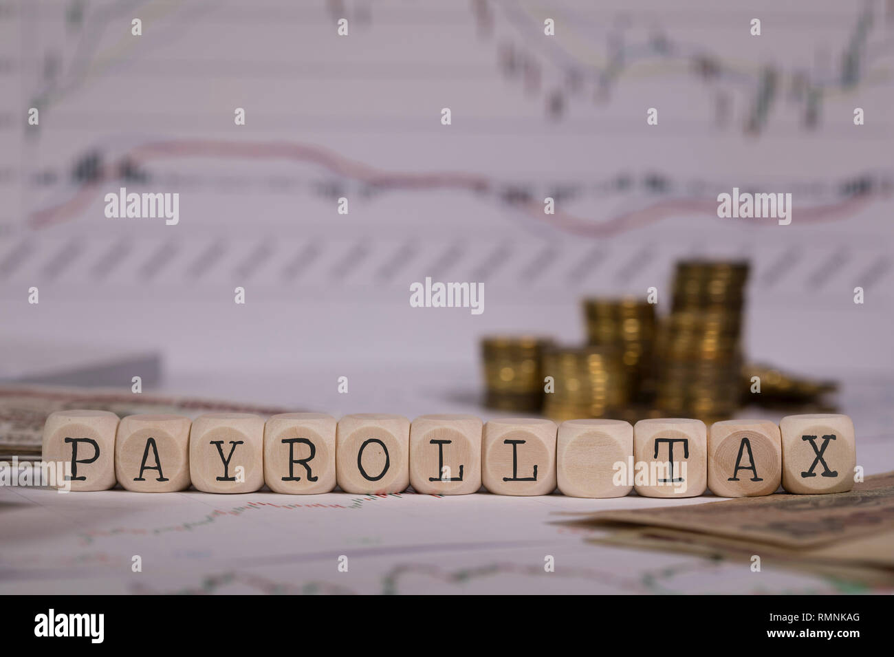 Words PAYROLL TAX composed of wooden letter. Stacks of coins in the ...