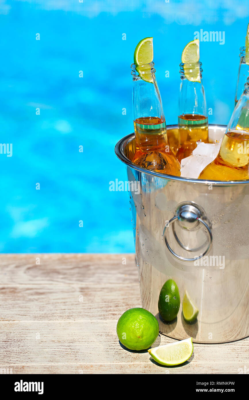 Closeup view of bucket with ice cubes, beer bottles and lime slices by ...