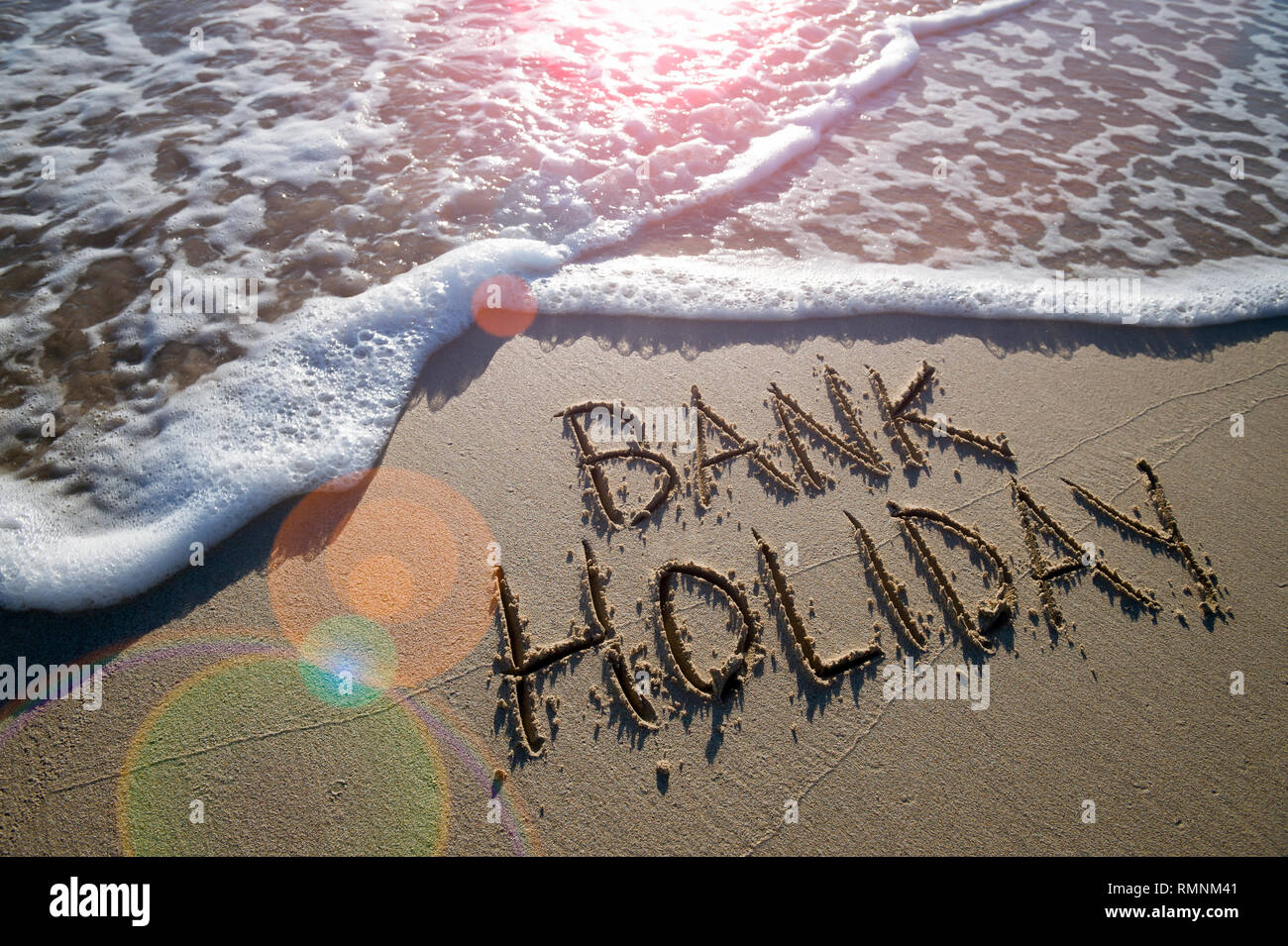 Bank Holiday message handwritten on the smooth sand of an empty beach ...