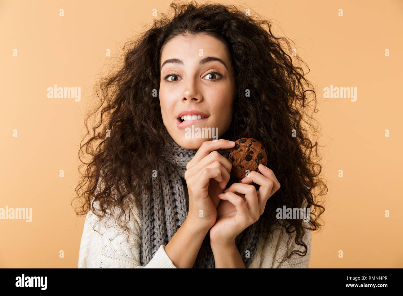 Happy young woman wearing winter scarf standing isolated over beige ...