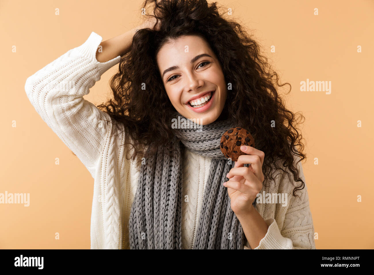 Happy young woman wearing winter scarf standing isolated over beige ...