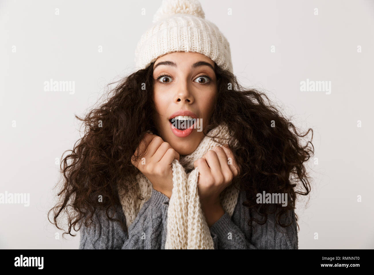 Cheerful young woman wearing winter scarf standing isolated over white ...