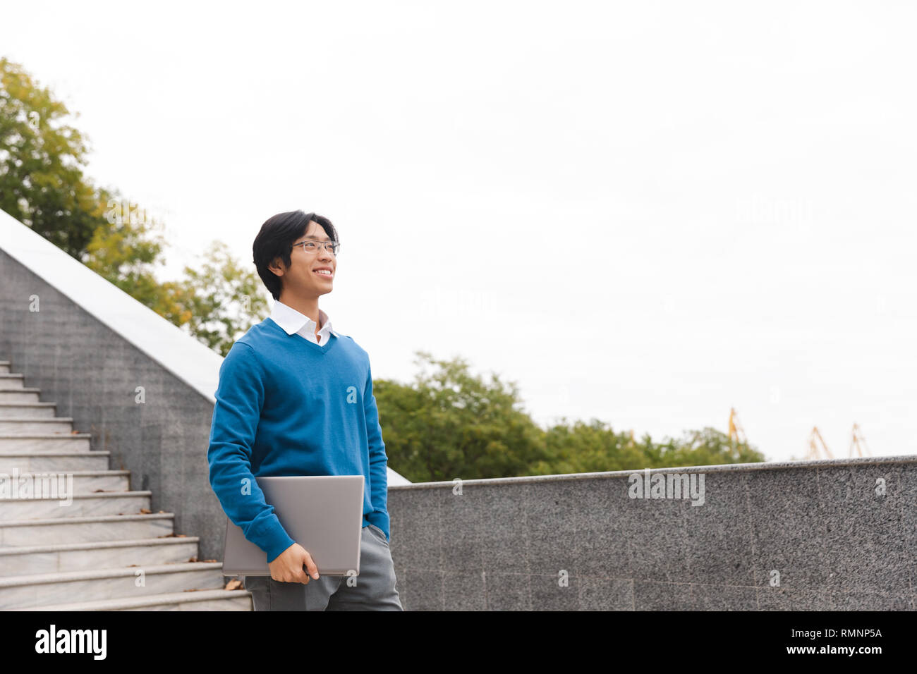 Smiling asian business man carrying laptop computer outdoors Stock ...