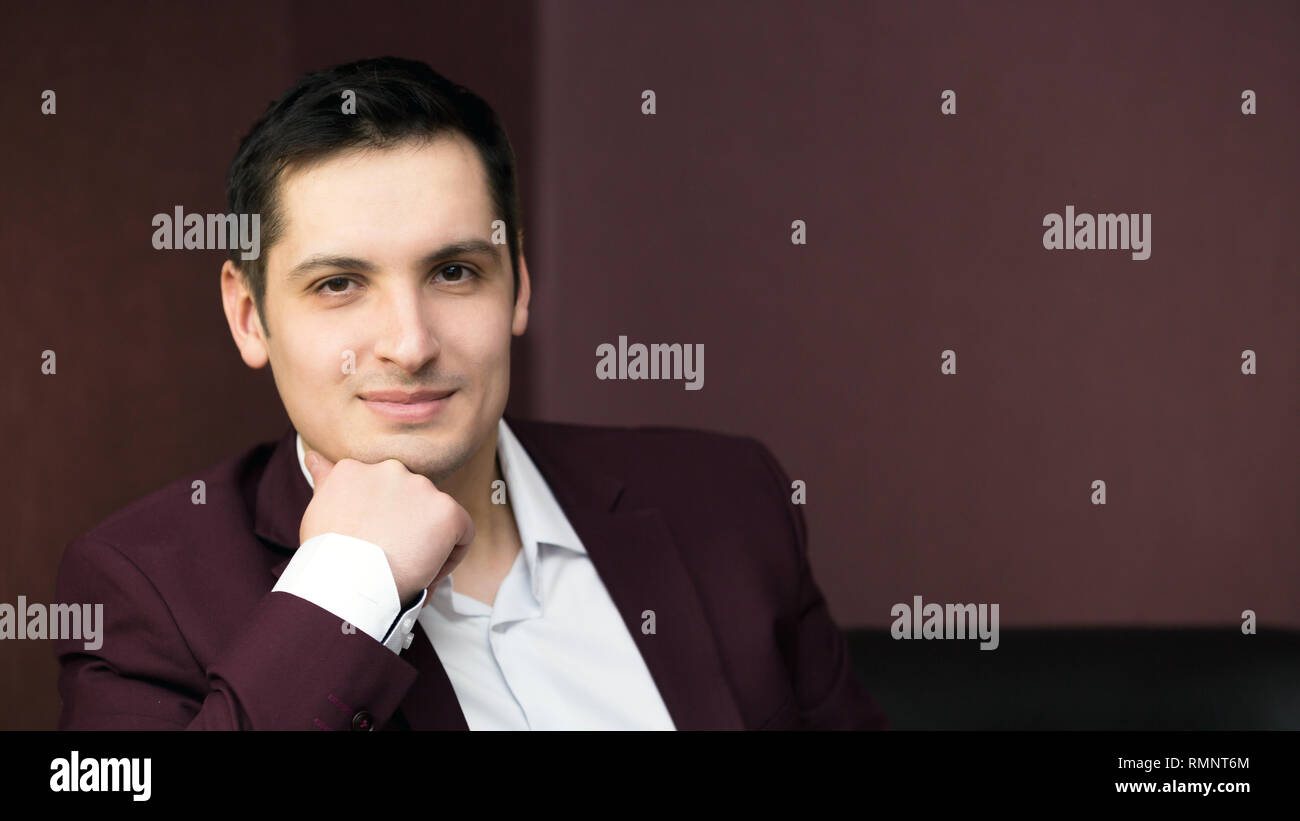 Male European appearance in a red suit on a dark background, blank for ...