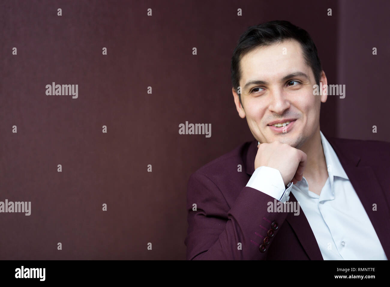 Male European appearance in a red suit on a dark background, blank for ...