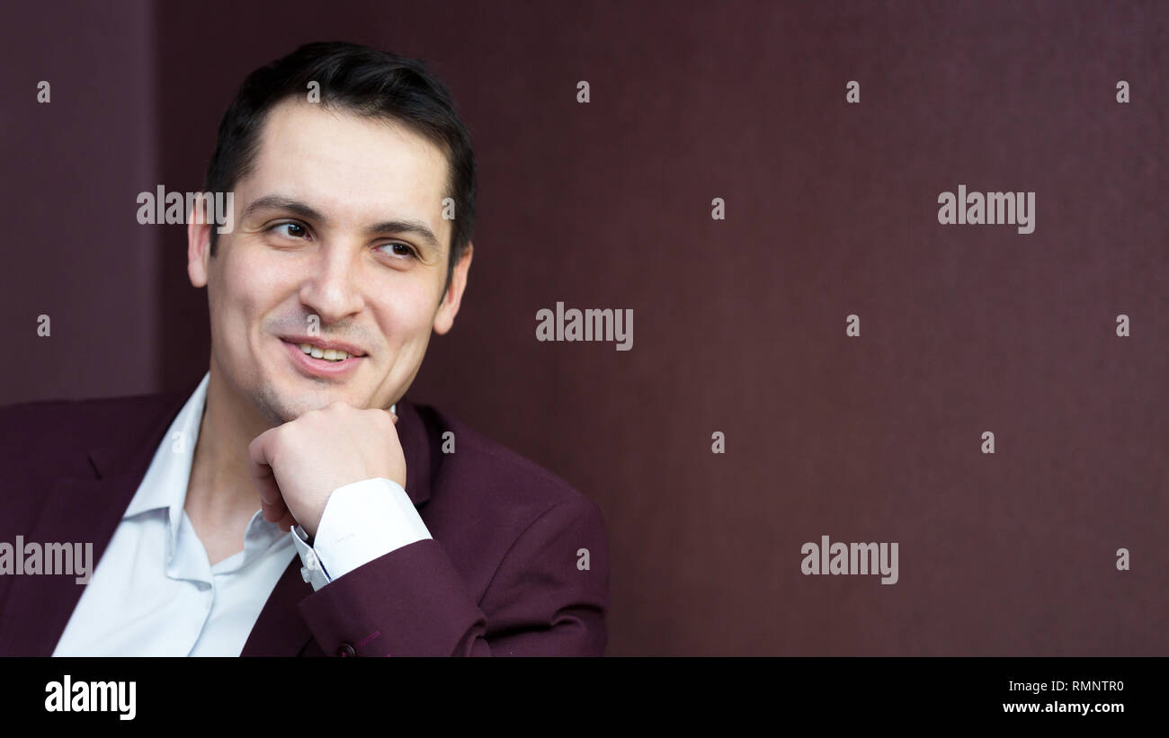 Male European appearance in a red suit on a dark background, blank for ...