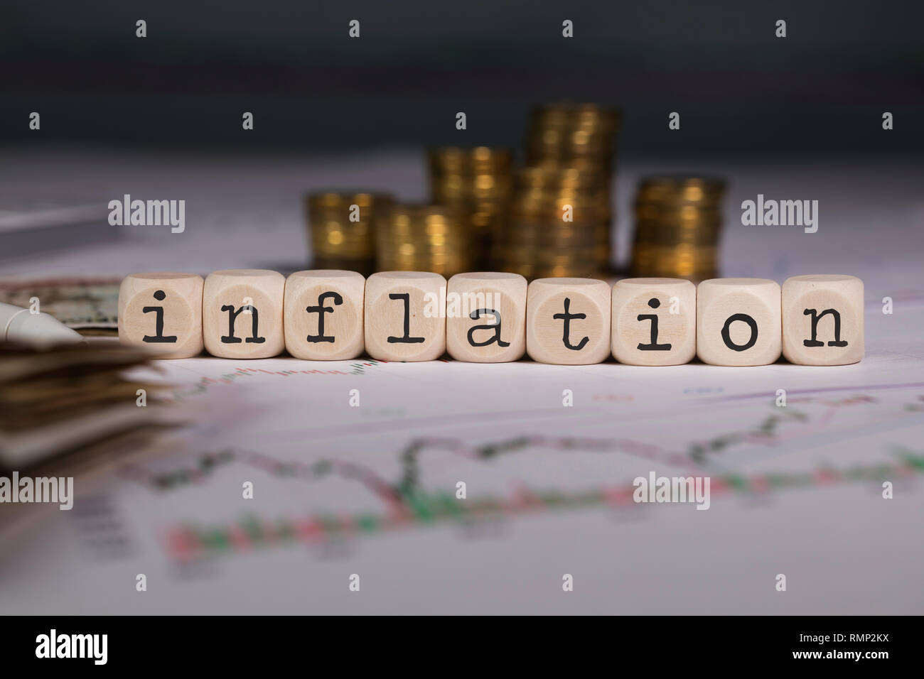Word INFLATION composed of wooden letter. Stacks of coins in the ...
