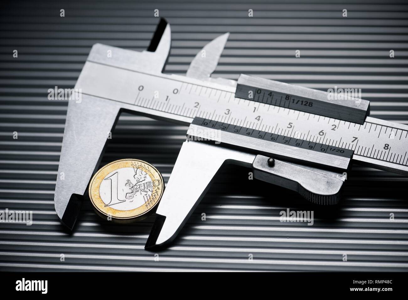 metal gauge measuring a one euro coin on a metal surface Stock Photo ...