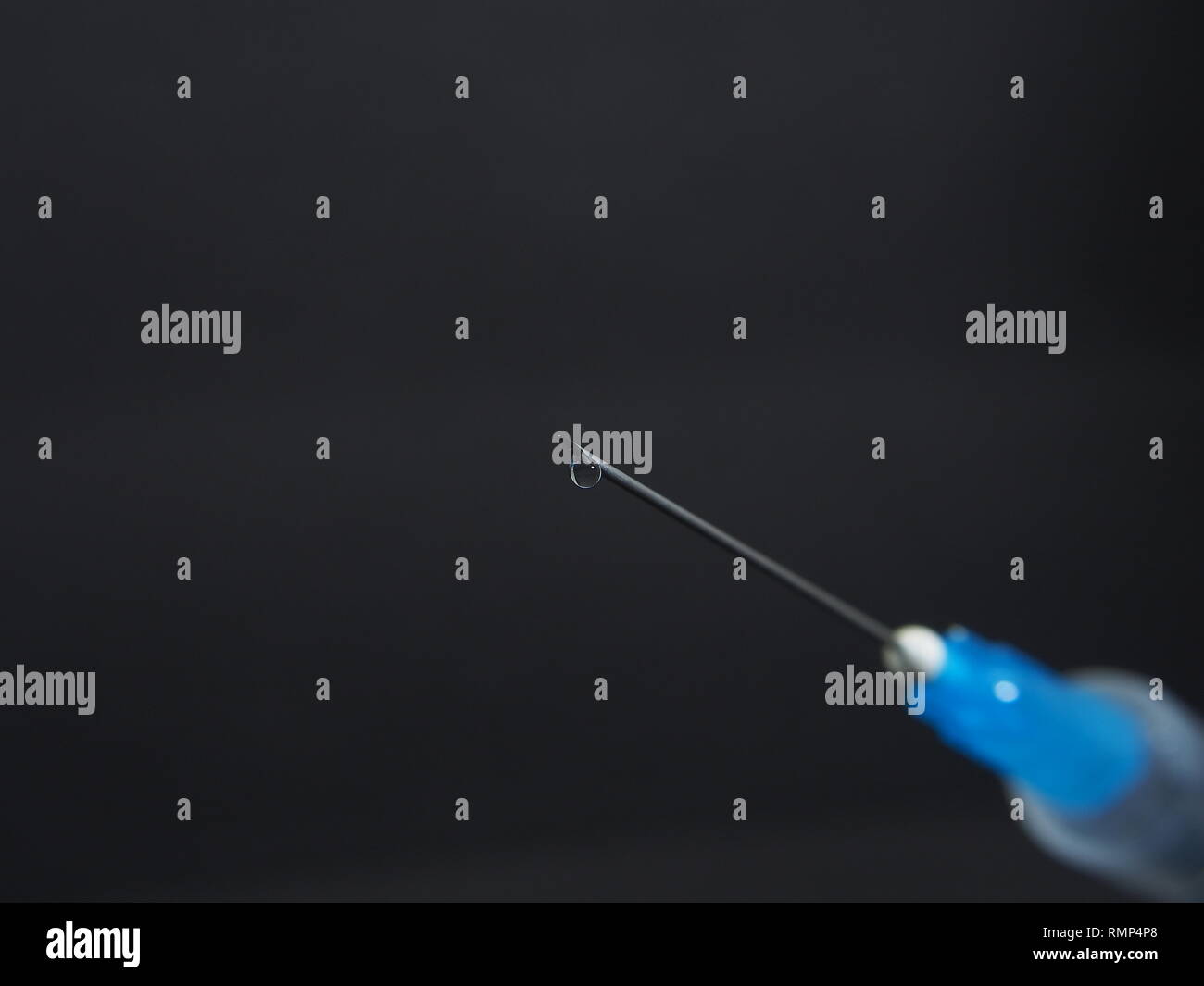 A drop of medicine on the end of a medical syringe needle. Photo on a ...