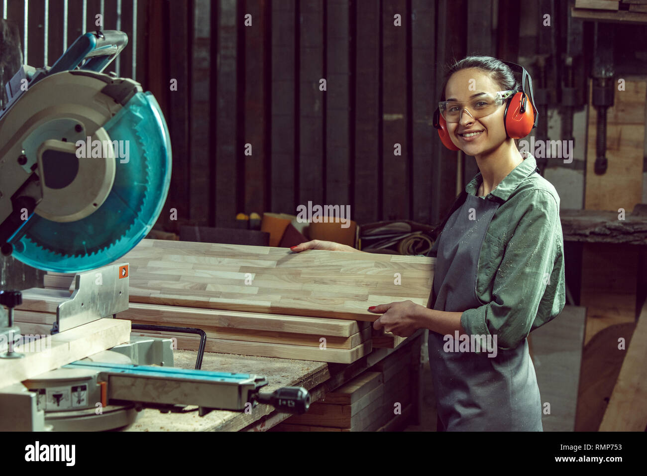 Smiling craftswoman grinding timbers with special machine. Beautiful ...