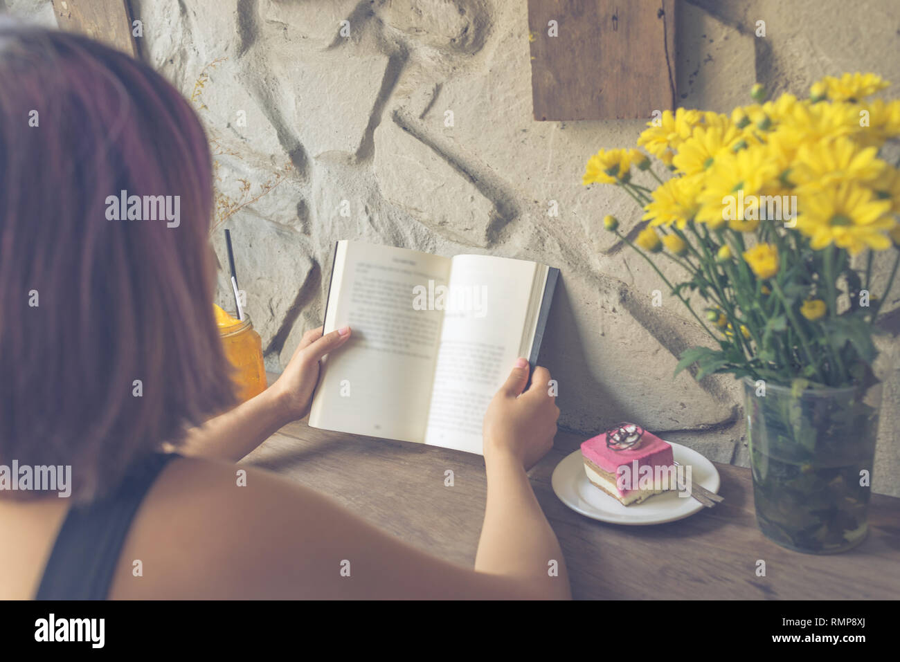 Rear view of young girl reading book at the cafe Stock Photo - Alamy