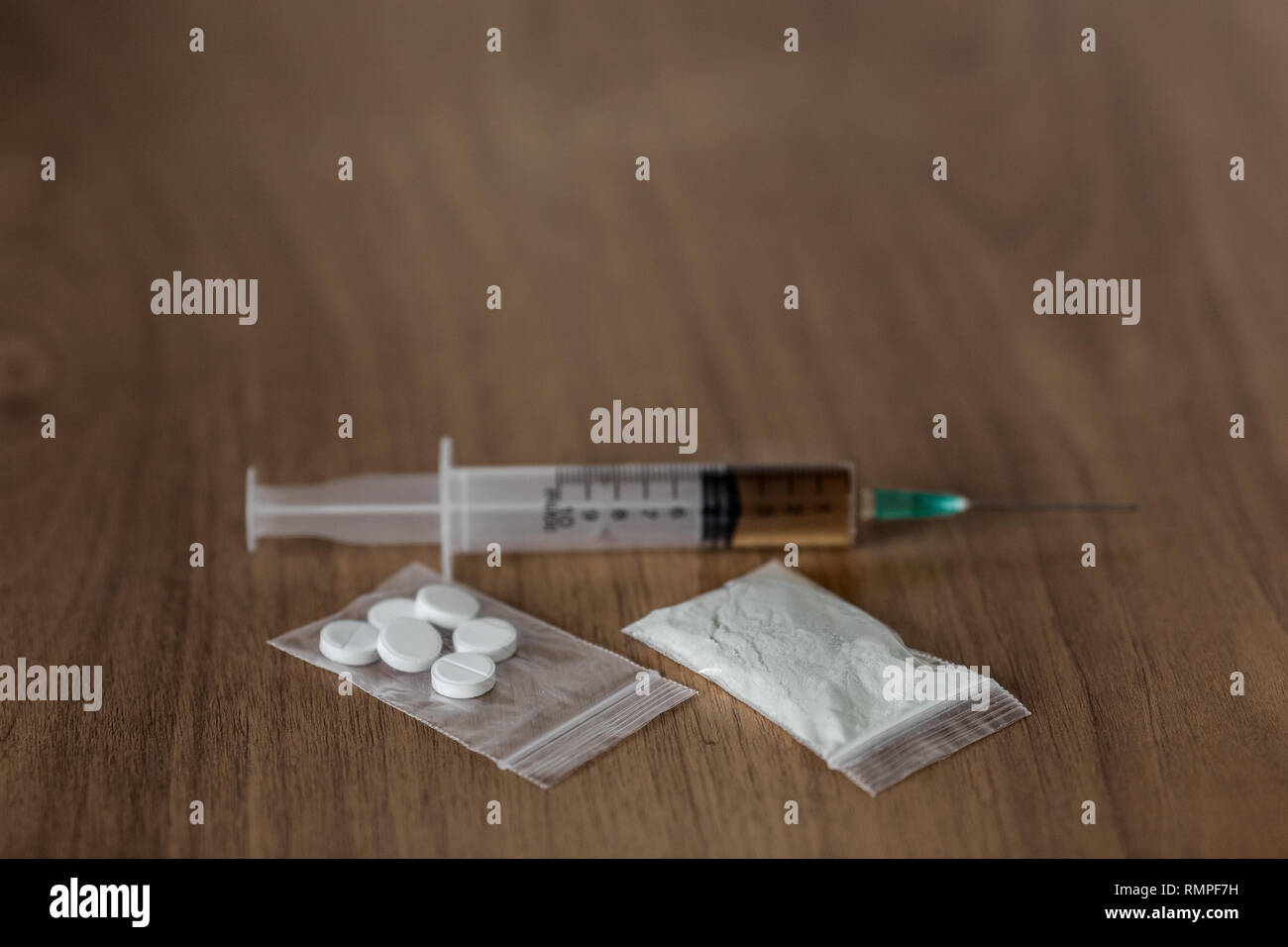 plastic packet with cocaine powder or another drugs. syringe on wooden ...