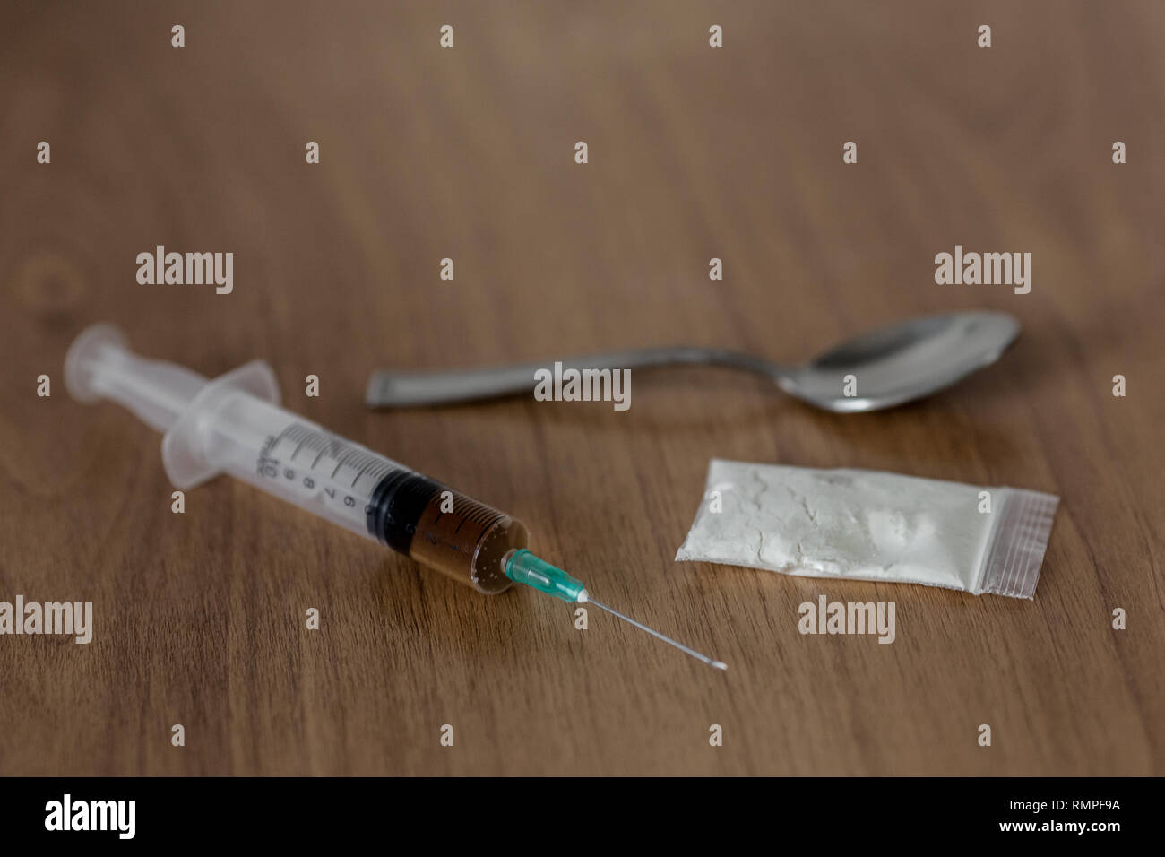 spoon, plastic packet with cocaine and syringe on the wooden table ...