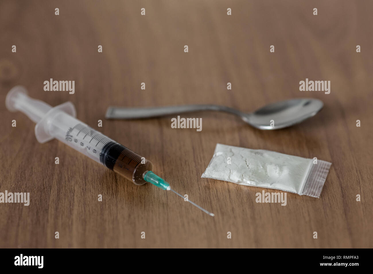 spoon, plastic packet with cocaine and syringe on the wooden table ...