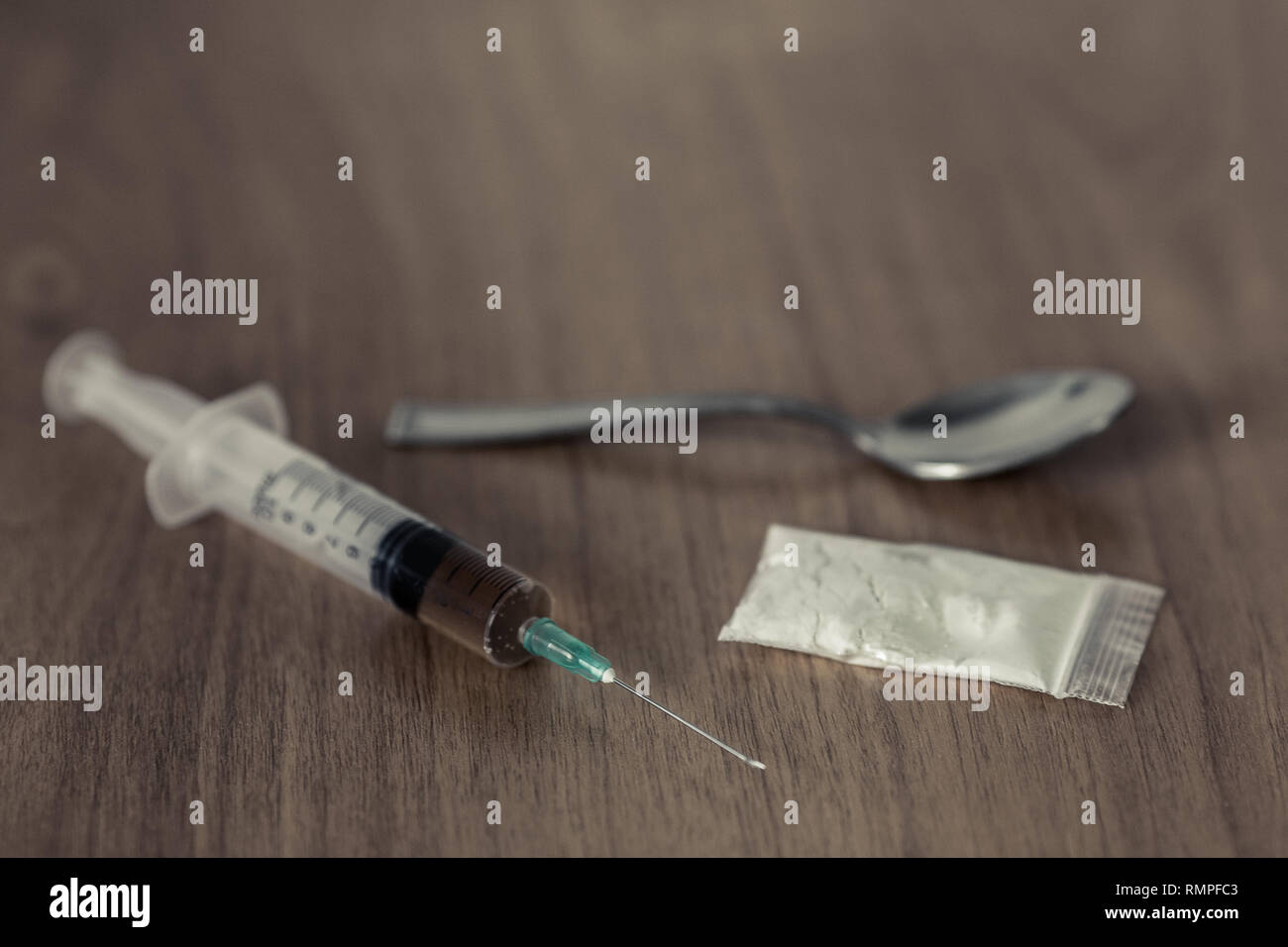 spoon, plastic packet with cocaine and syringe on the wooden table ...