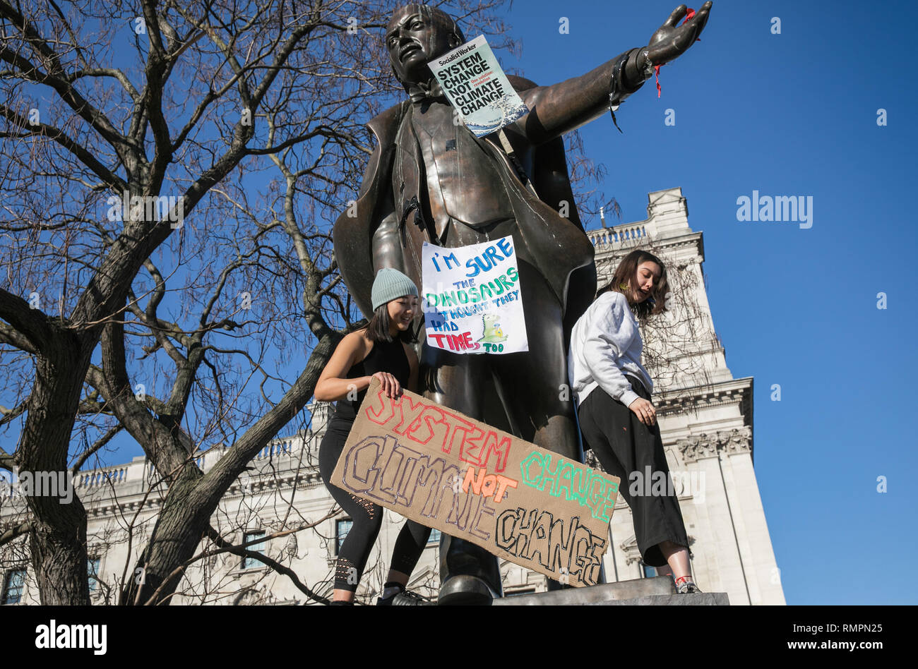 Two female students climb on the statues to display their banners ...