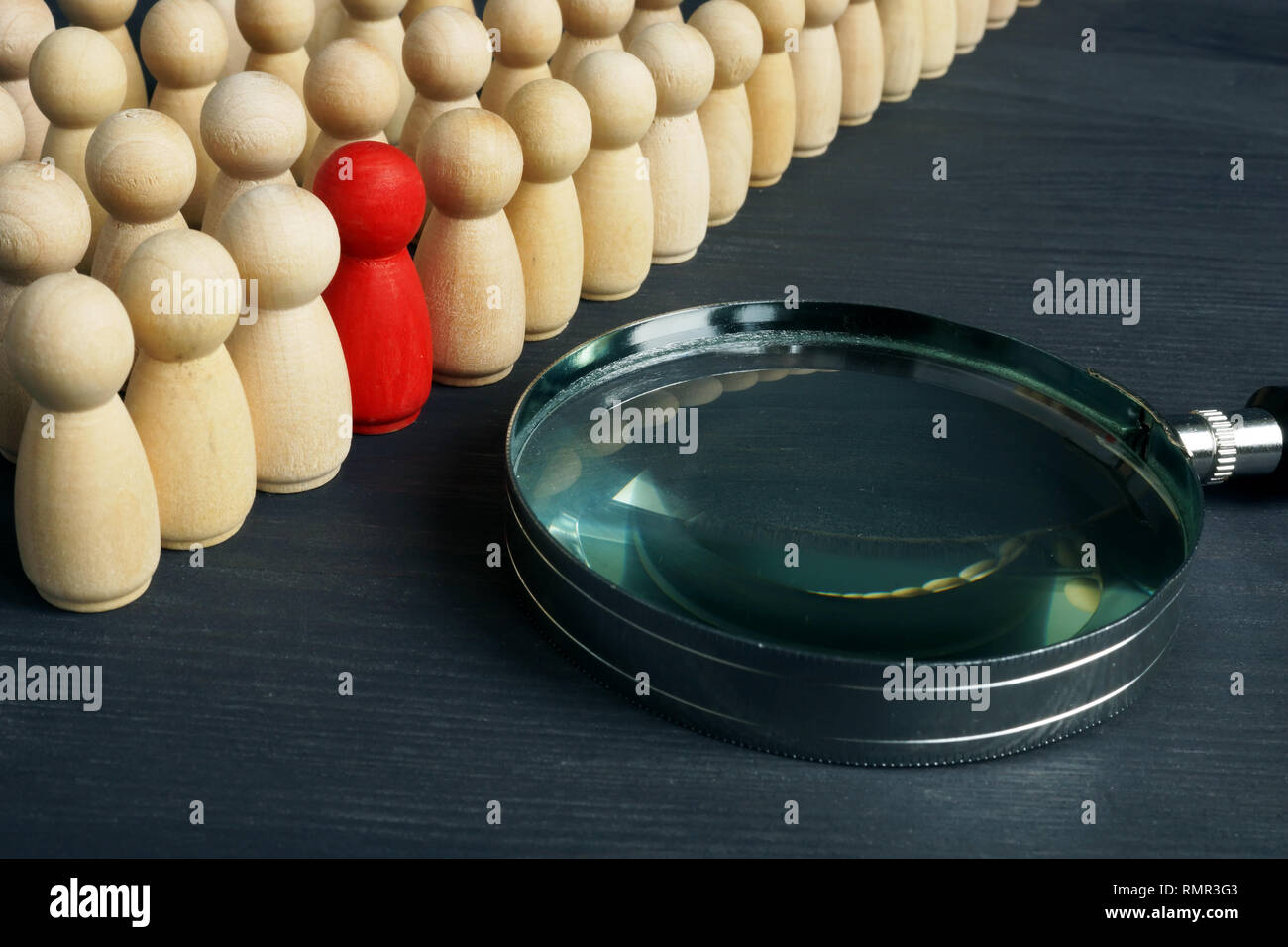 Magnifying glass and wooden figurines. Individuality and uniqueness ...