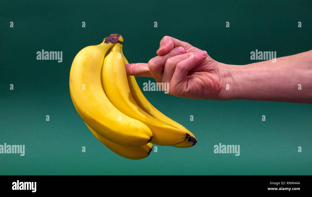 bunch of yellow bananas in man hand on green background Stock Photo - Alamy