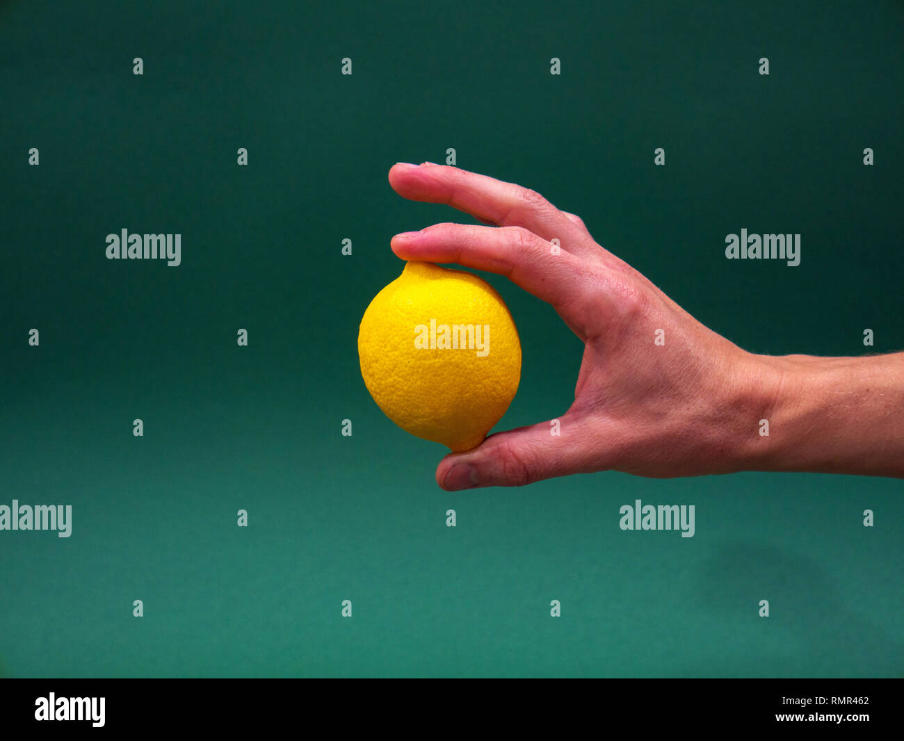 Lemon in mens hand on green background isolation Stock Photo - Alamy