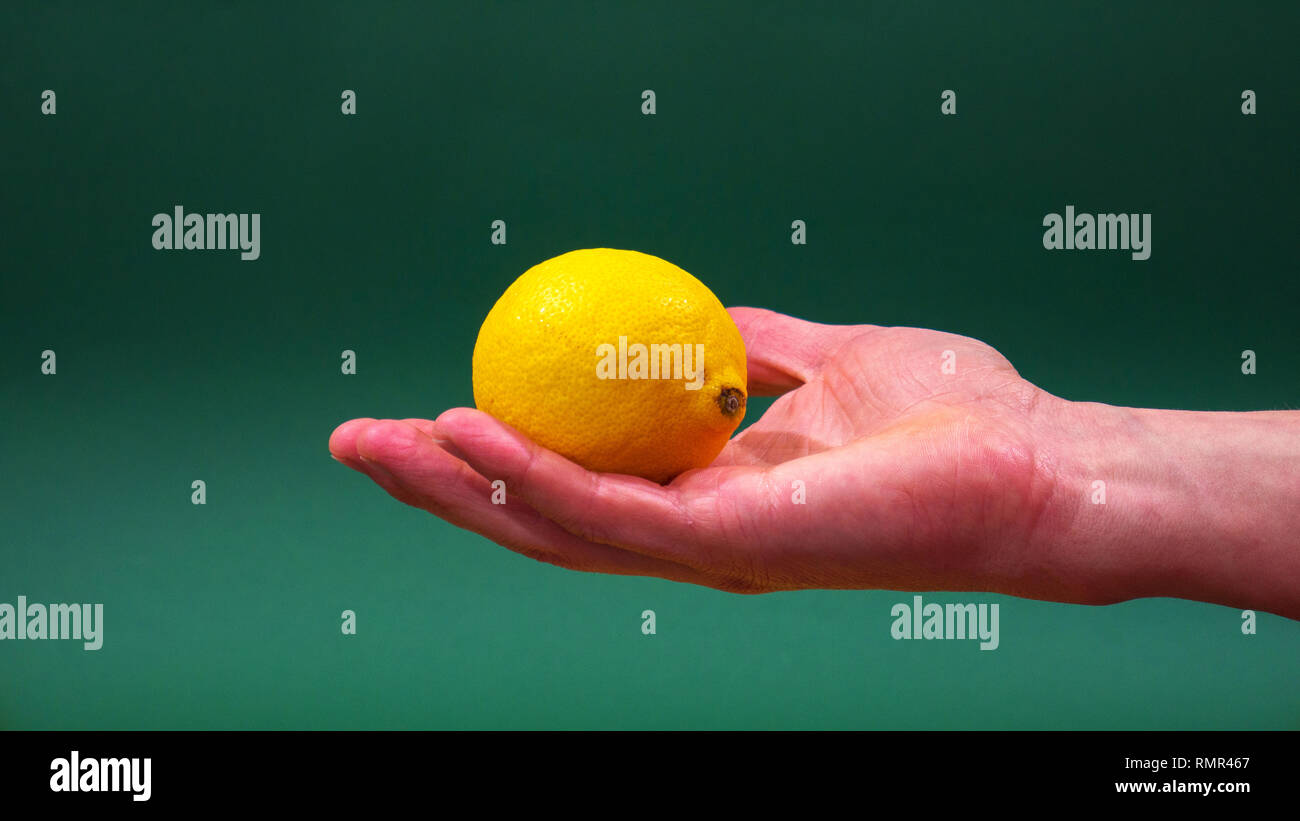 Lemon in mens hand on green background isolation Stock Photo - Alamy