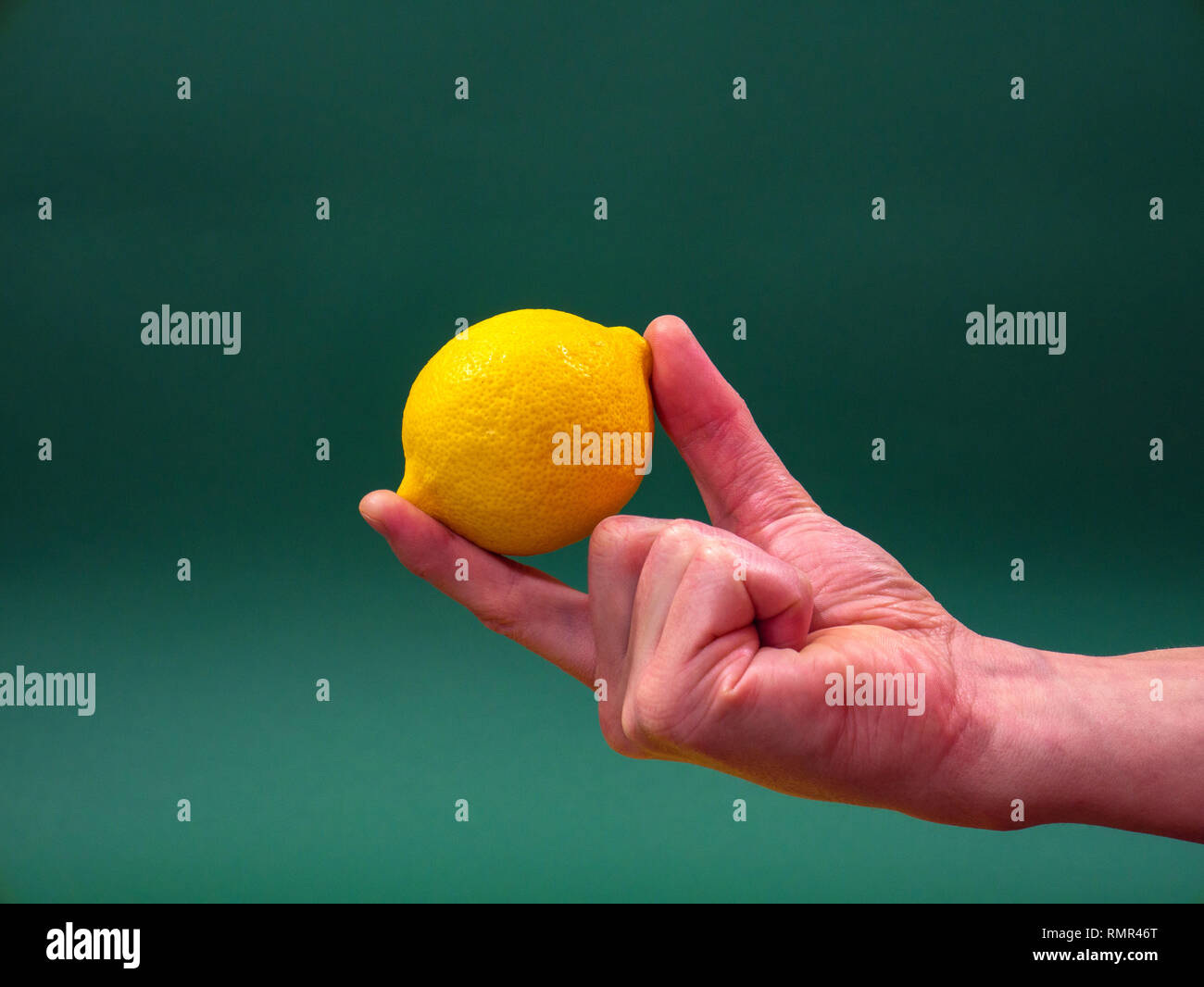 Lemon in mens hand on green background isolation Stock Photo - Alamy