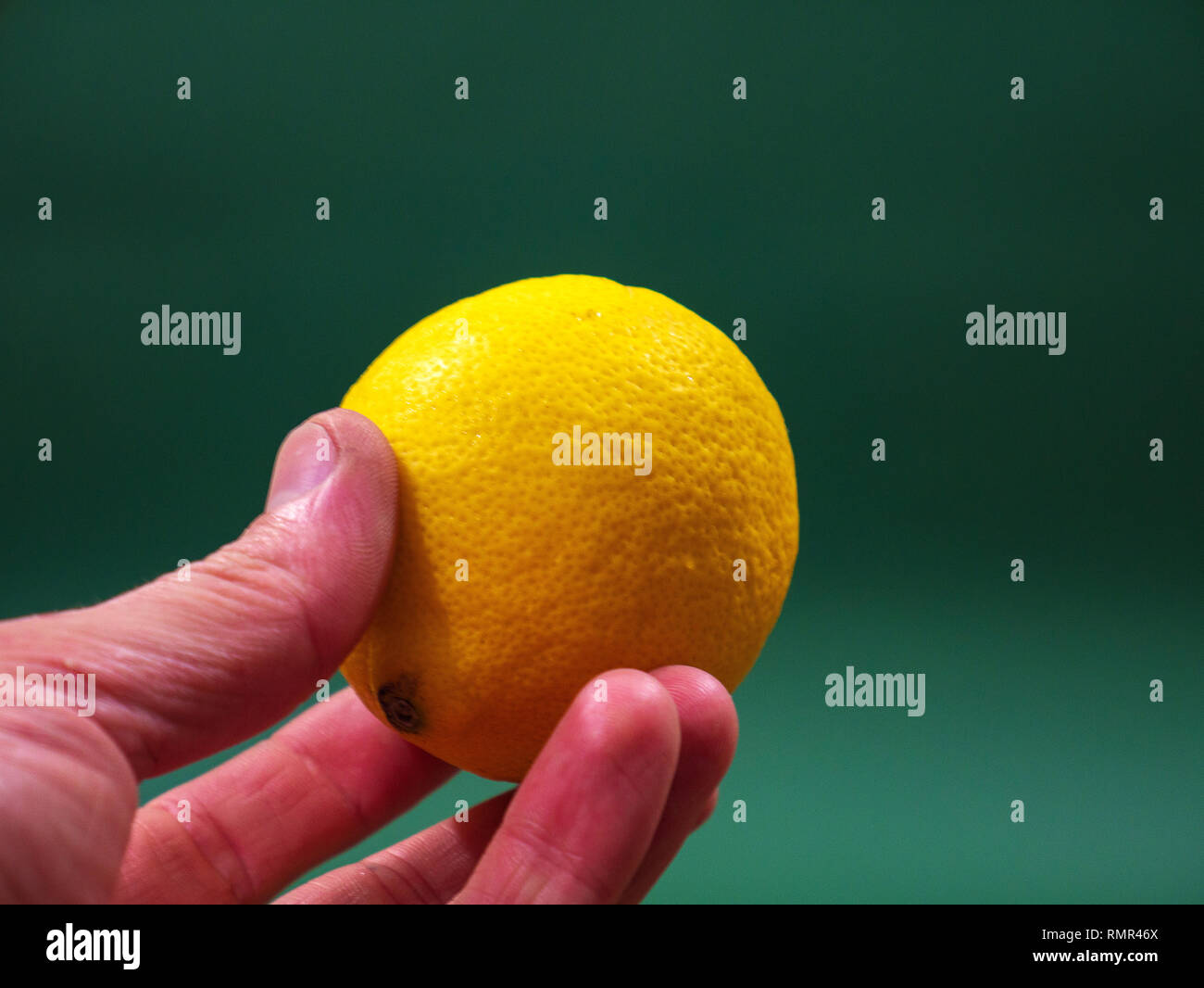 Lemon in mens hand on green background isolation Stock Photo - Alamy