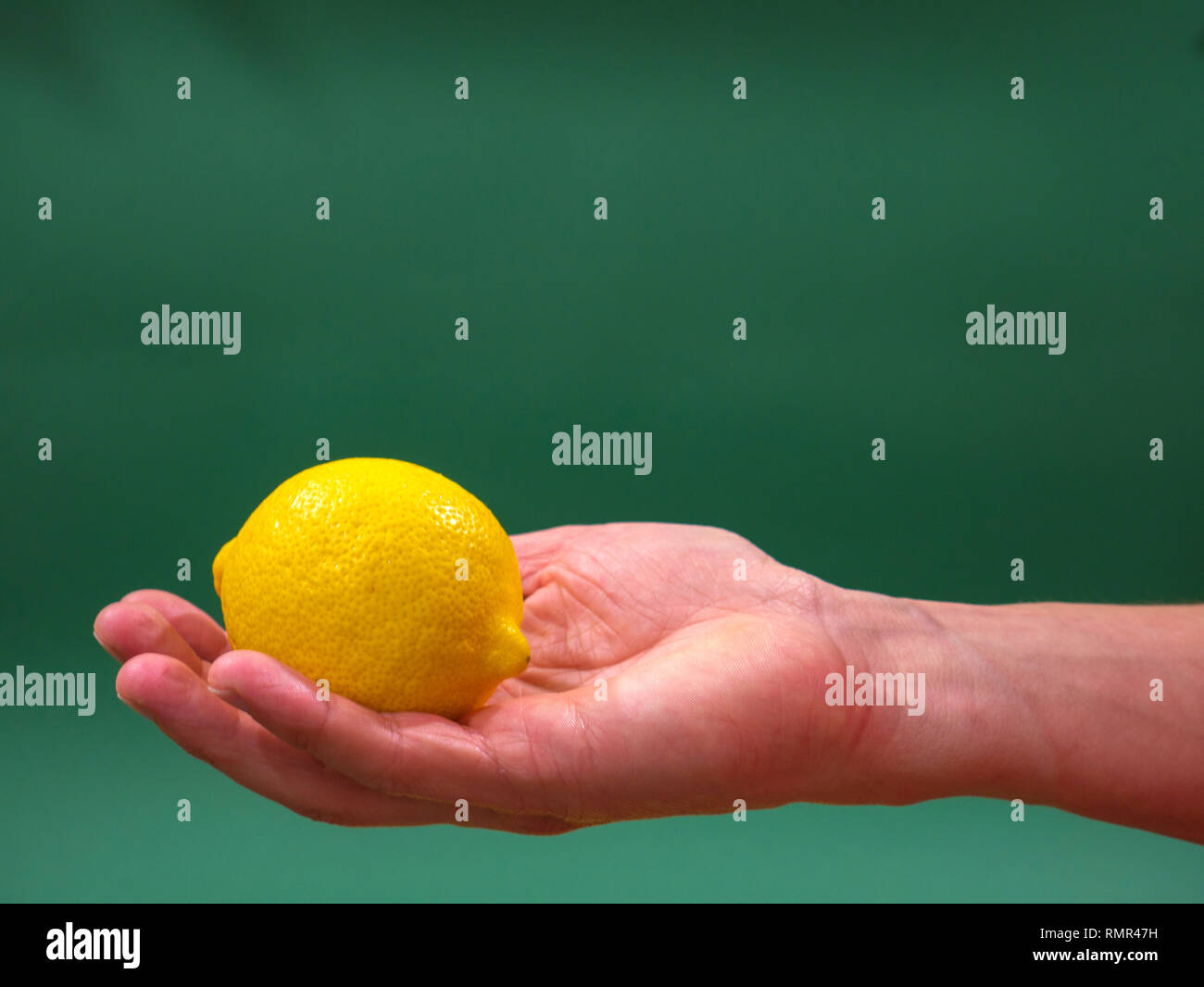 Lemon in mens hand on green background isolation Stock Photo - Alamy