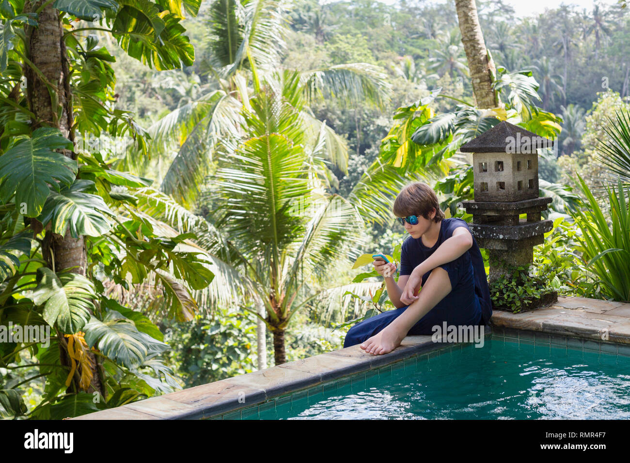 Teenage boy at swimming pool using cell phone Stock Photo - Alamy
