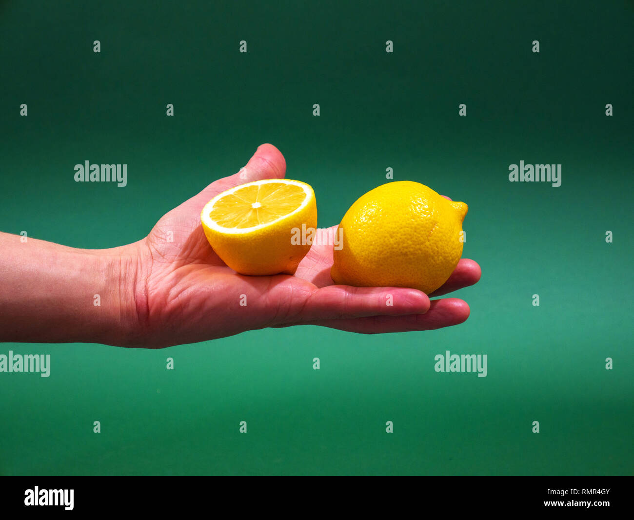 Lemon in mens hand on green background isolation Stock Photo - Alamy
