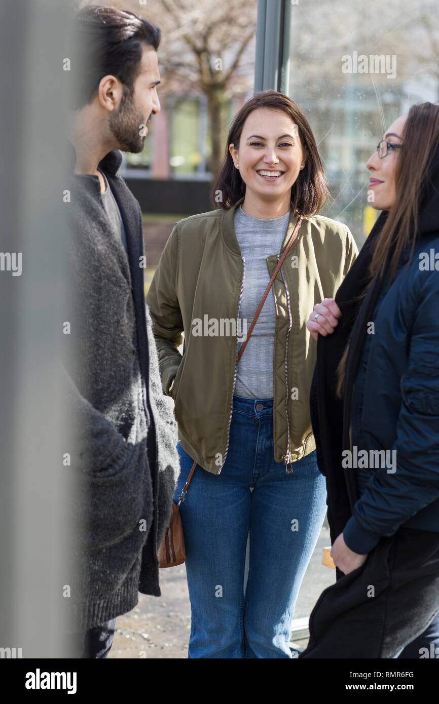 Friends talking on bus stop Stock Photo - Alamy