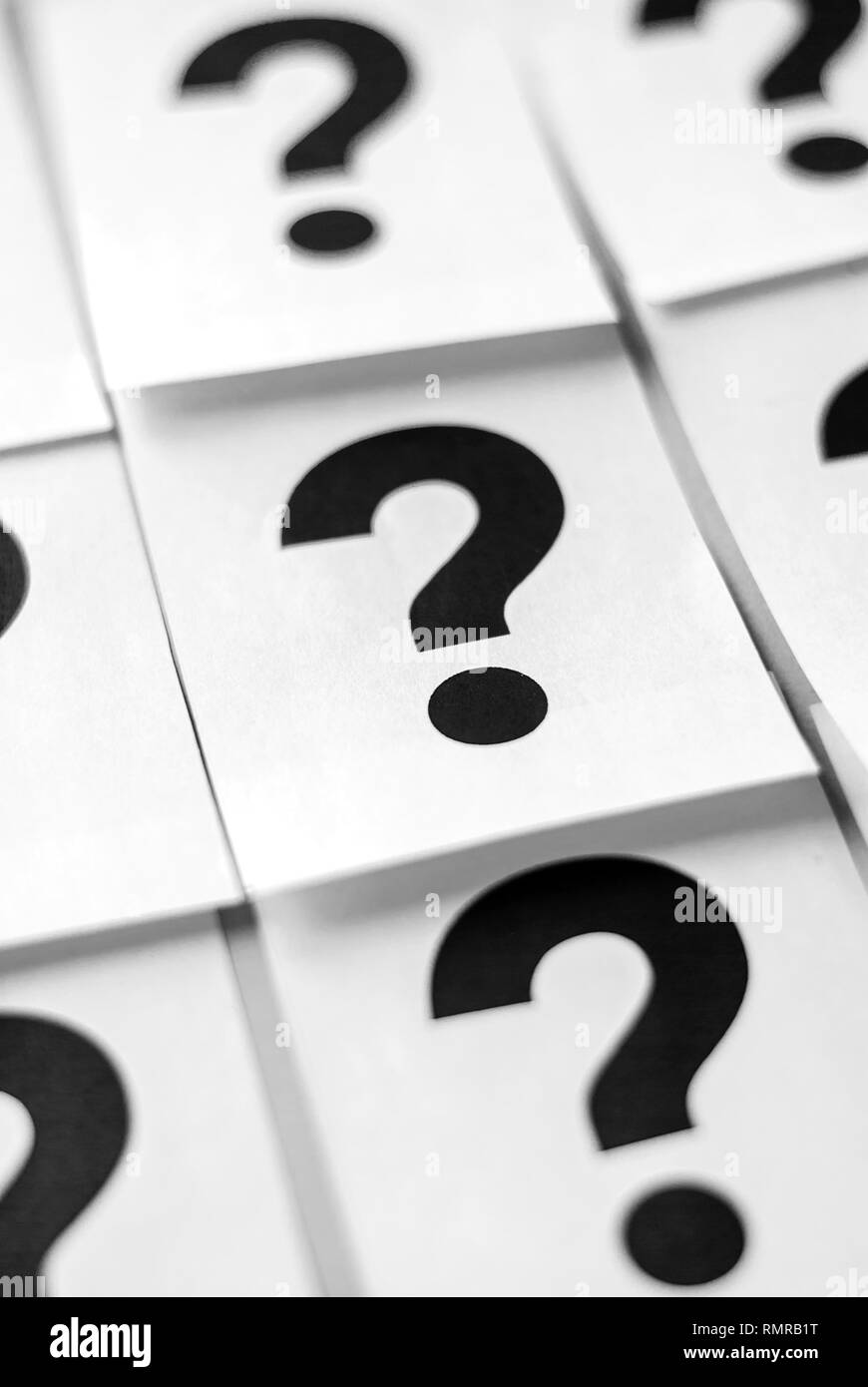 Black question marks printed on white sheets of paper arranged in full ...