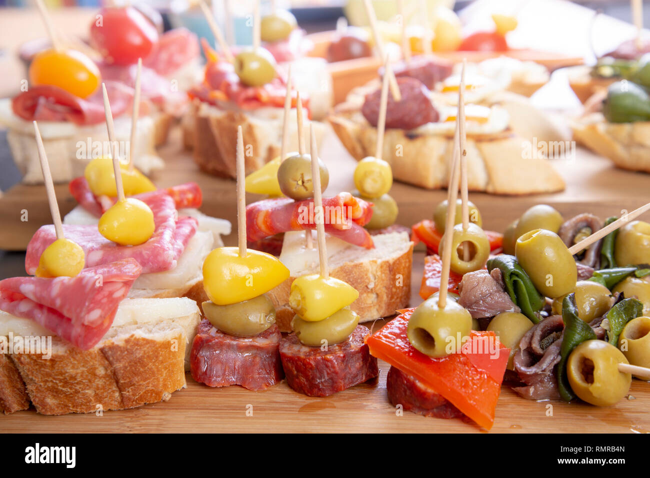 Sharing mixed spanish tapas starters on table. Olives, sandwiches and ...