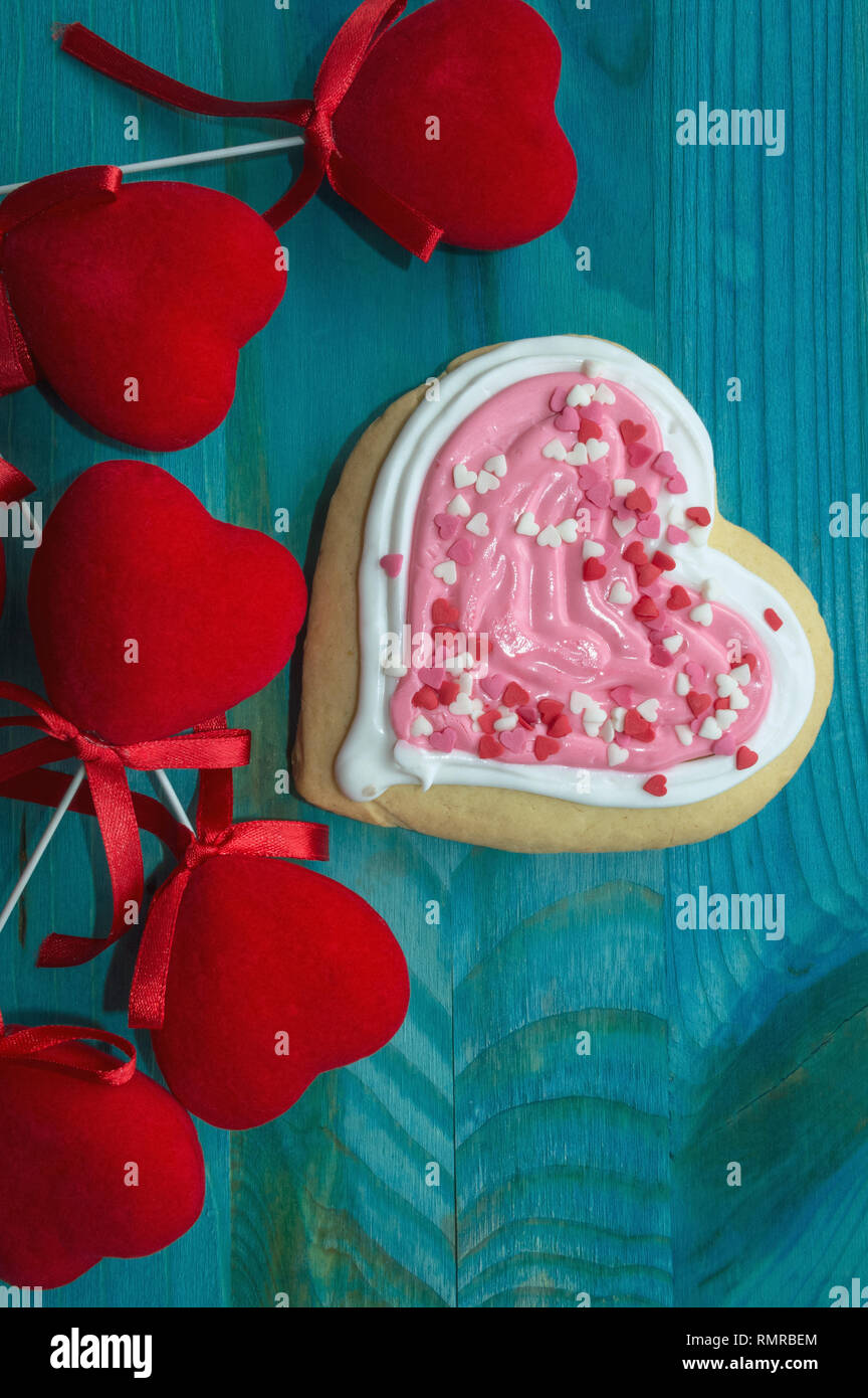 vertical image of heart shaped cookie and red velvet hearts decor on ...