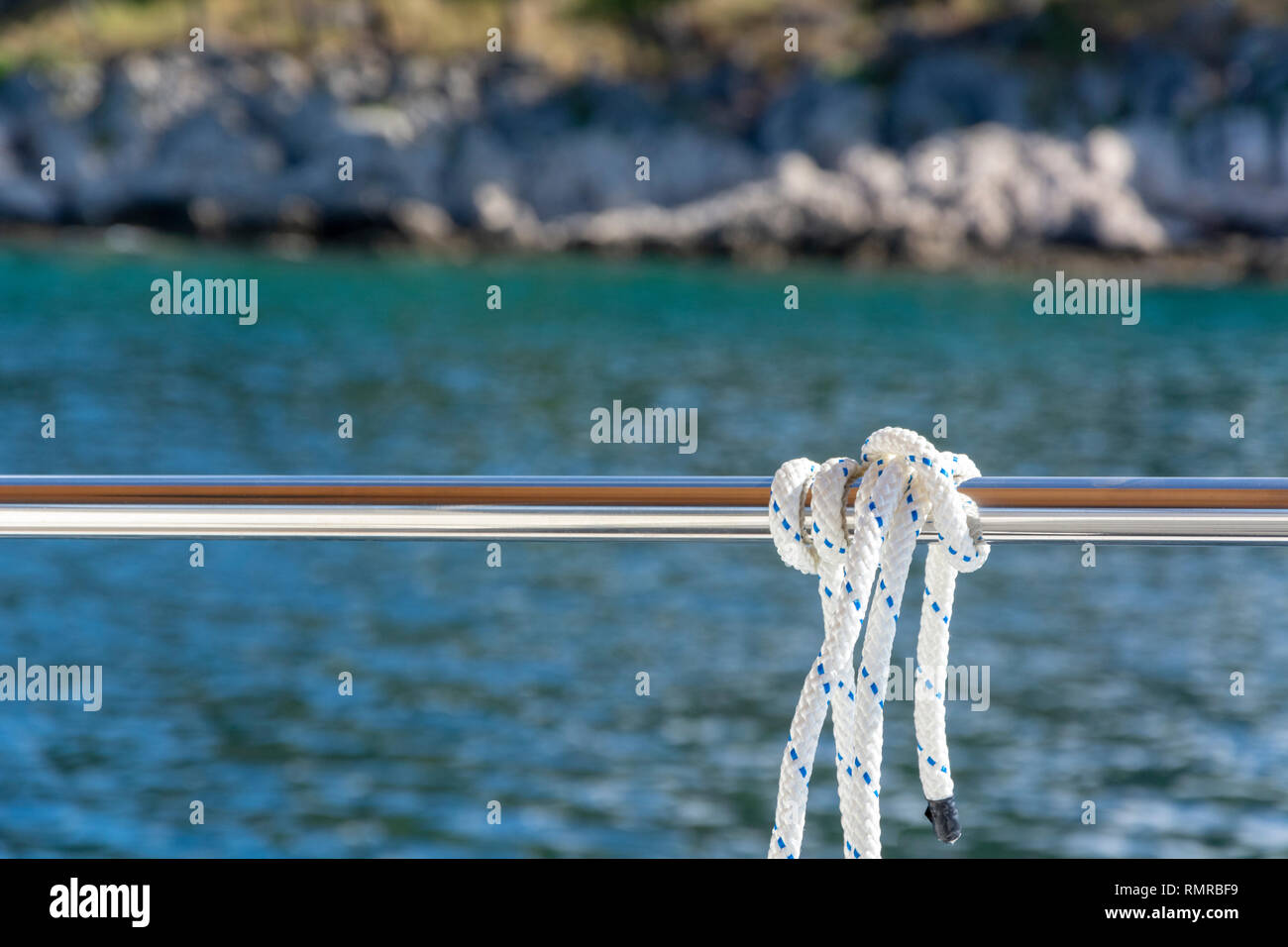White and blue rope tied up on the yacht's railing with blurred ...