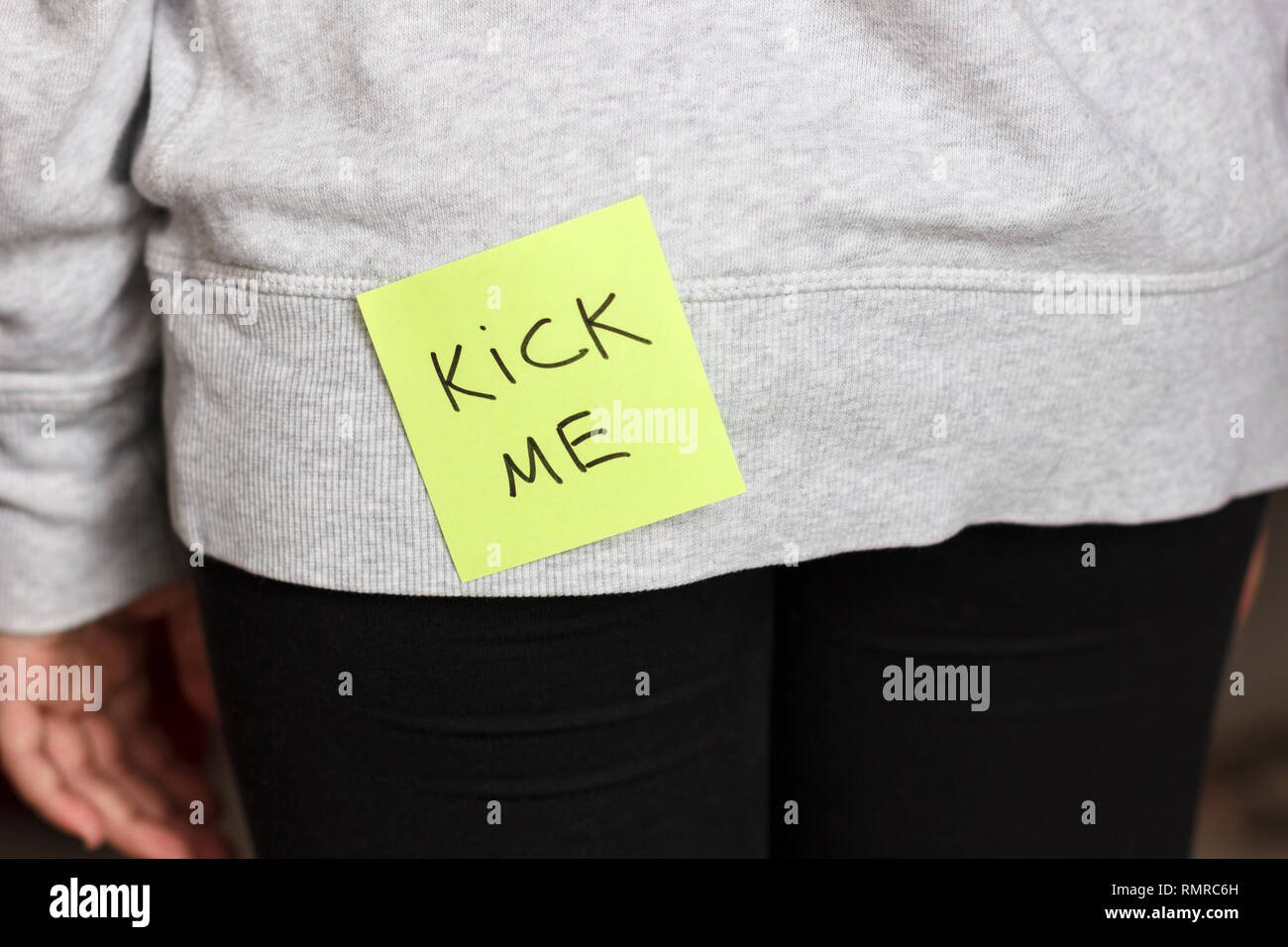 Sticker 'Kick me' on teenager girl's back. 1 april joke Stock Photo - Alamy