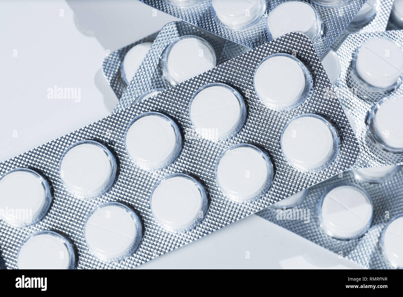 White pills in silver packaging on a white background Stock Photo - Alamy