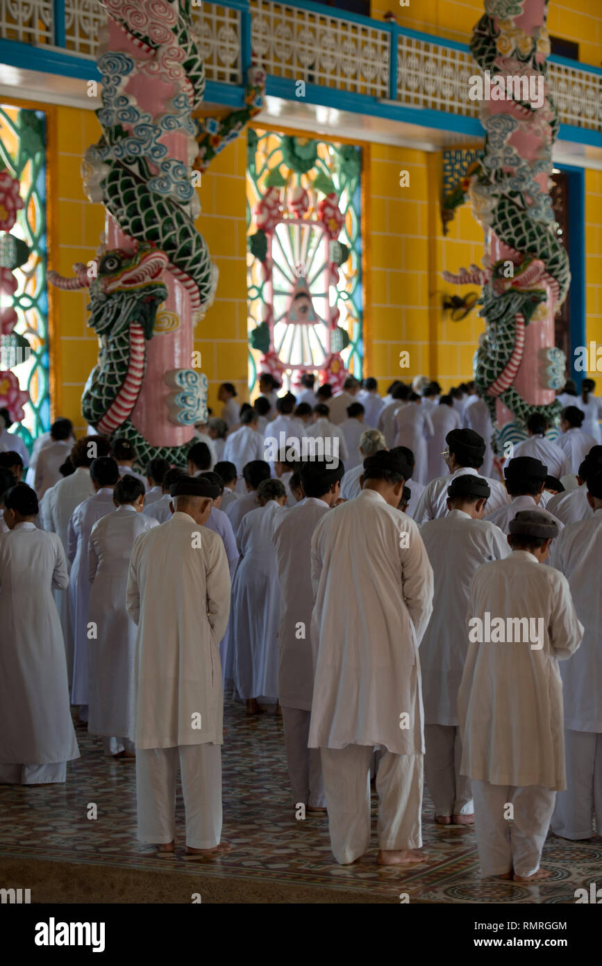 Caodaist disciples, standing by colorful columns with dragons, Cao Dai ...