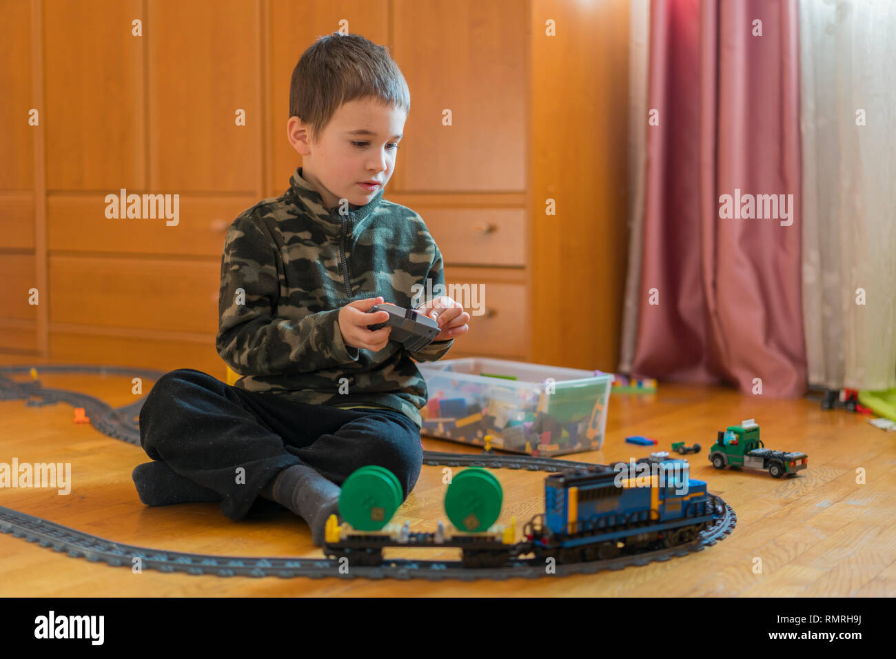Five year old boy playing on the floor by rail. Little boy playing with ...