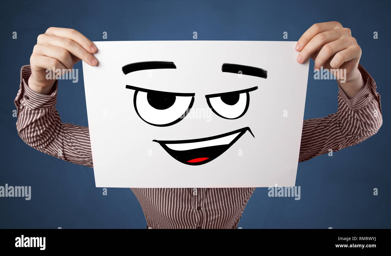 Casual person holding a paper in front of his face with drawn emoticon ...