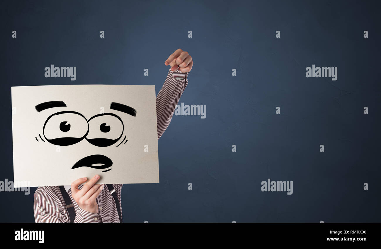 Casual person holding a paper with funny emoticon in front of her face ...