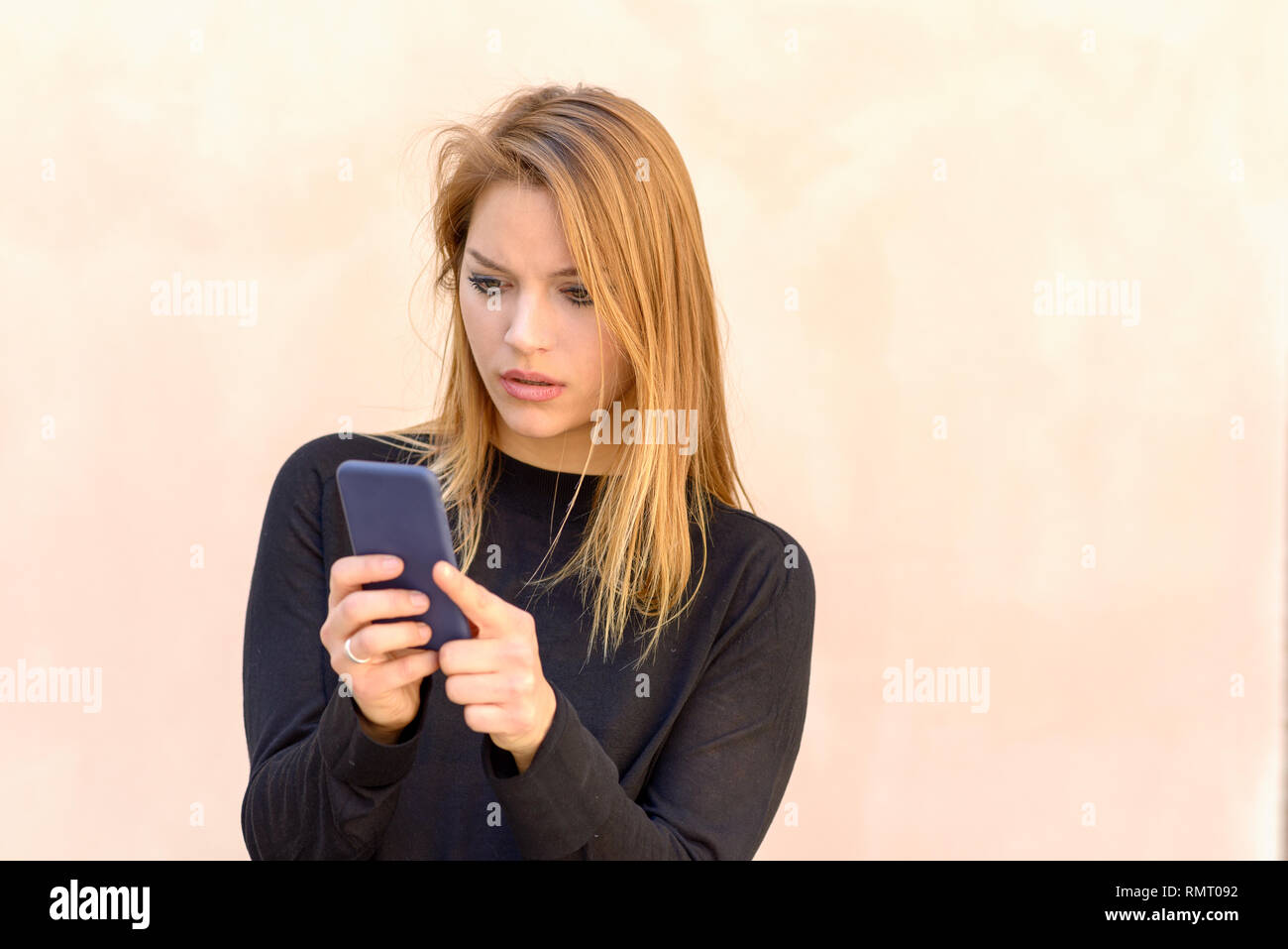 Engrossed attractive young woman reading a text message on her mobile ...