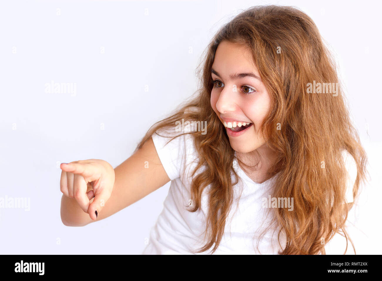 Teen girl laughs and points at something with her finger Stock Photo ...