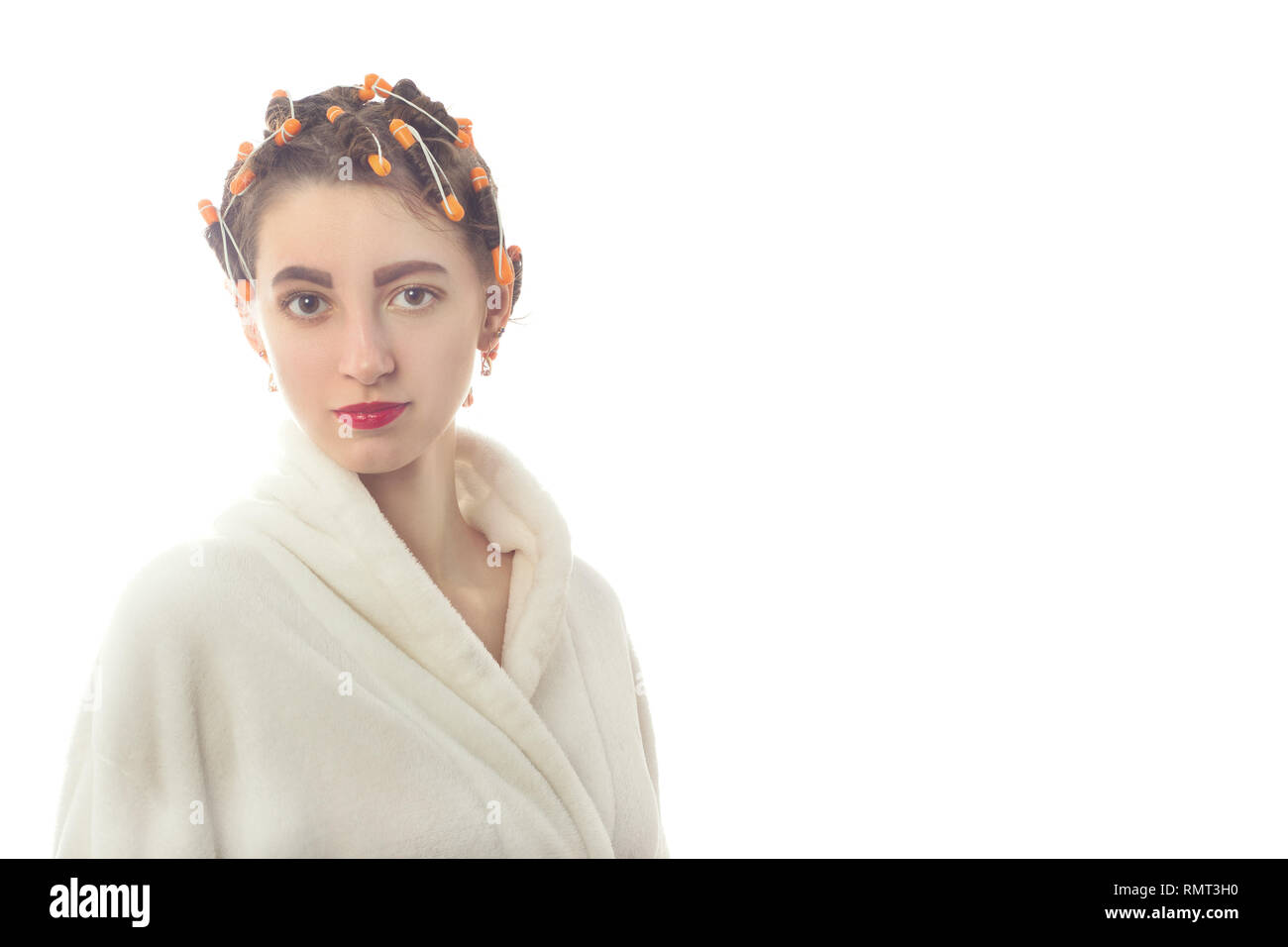 young woman with hair curlers on head and bathrobe isolated on white ...