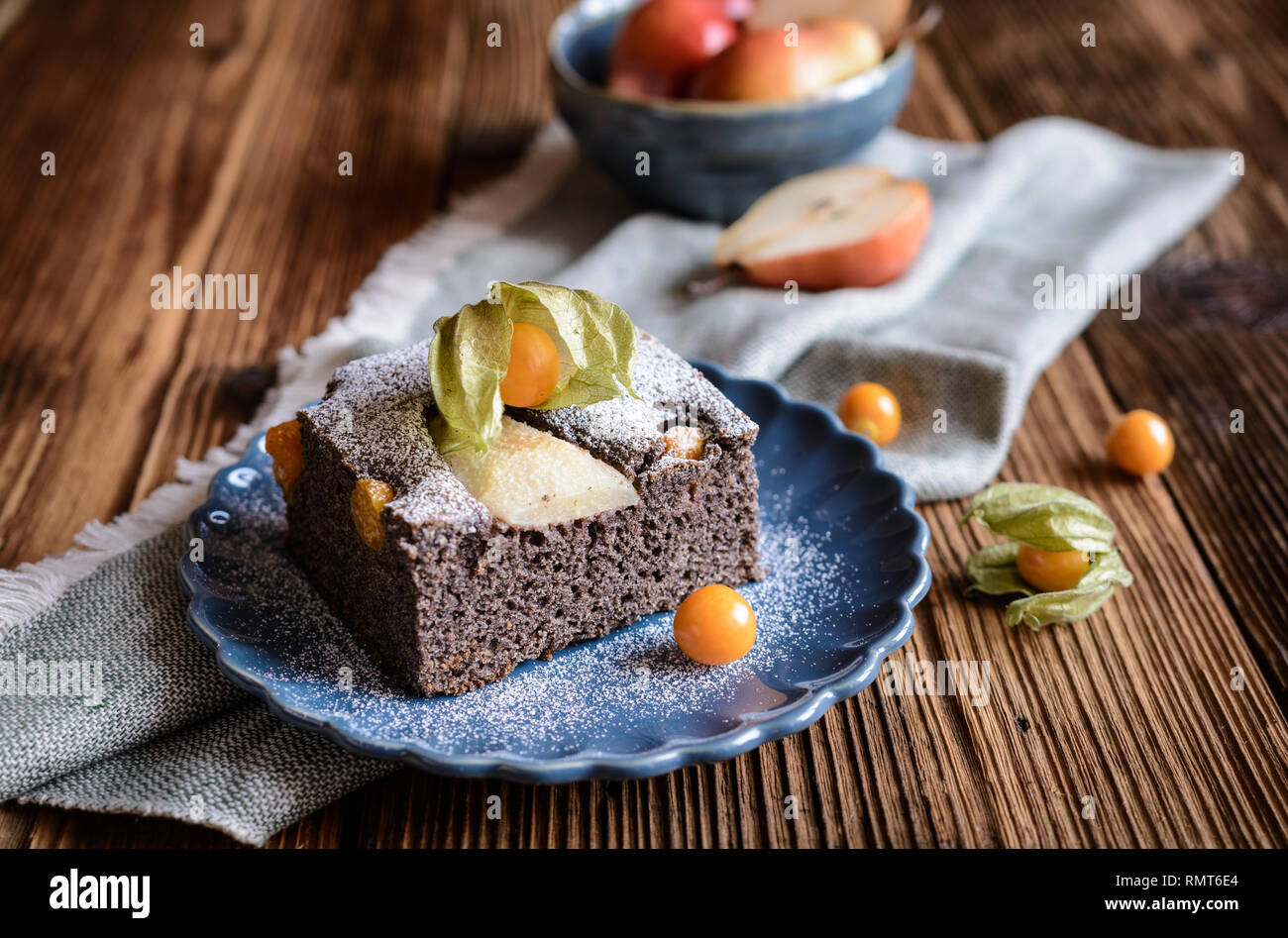 Poppy seed sponge cake with physalis and pear, sprinkled with powdered ...