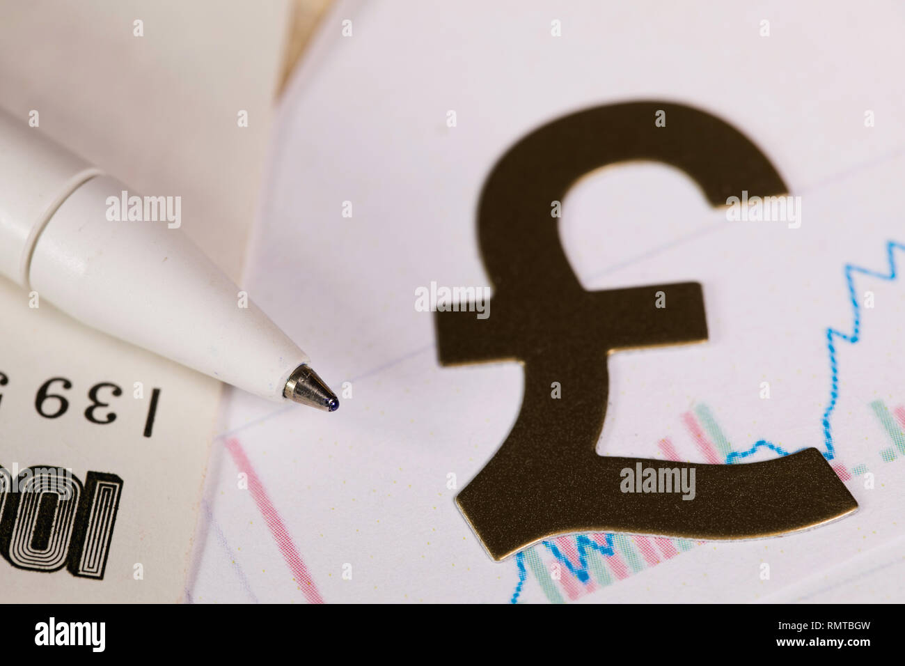 Pen on a banknote. Cutout of British pound sign in the background ...