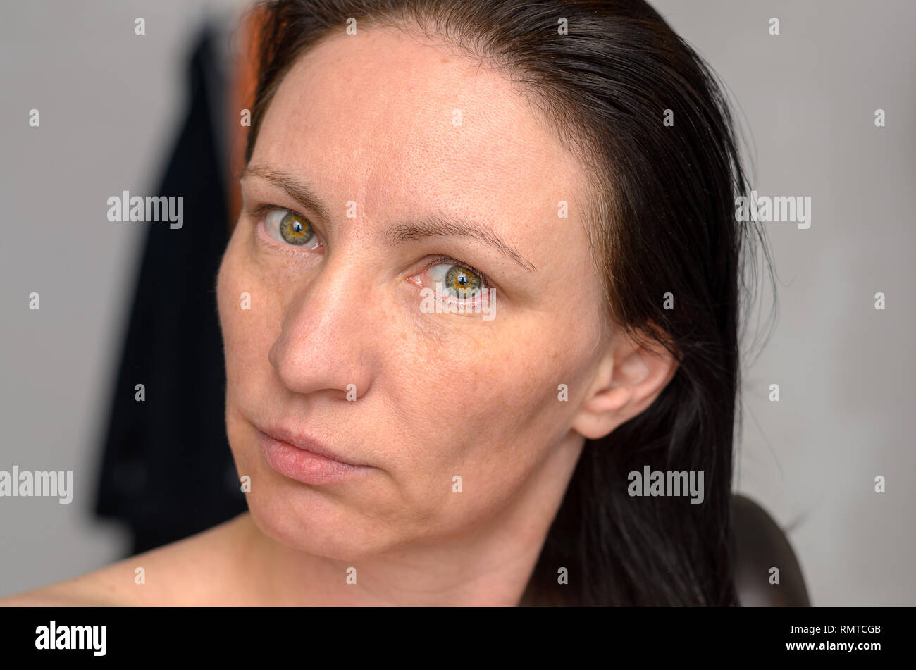 Woman with long brown hair bushing it with a hairbrush as she looks ...