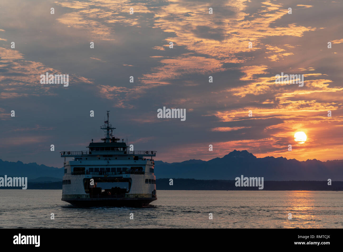 A ferry boat crossing Puget Sound at sunset near Seattle with Olympic ...