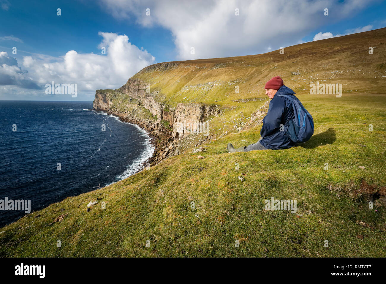 A walker sitting on the top of sea cliffs on Foula, Shetland Stock ...